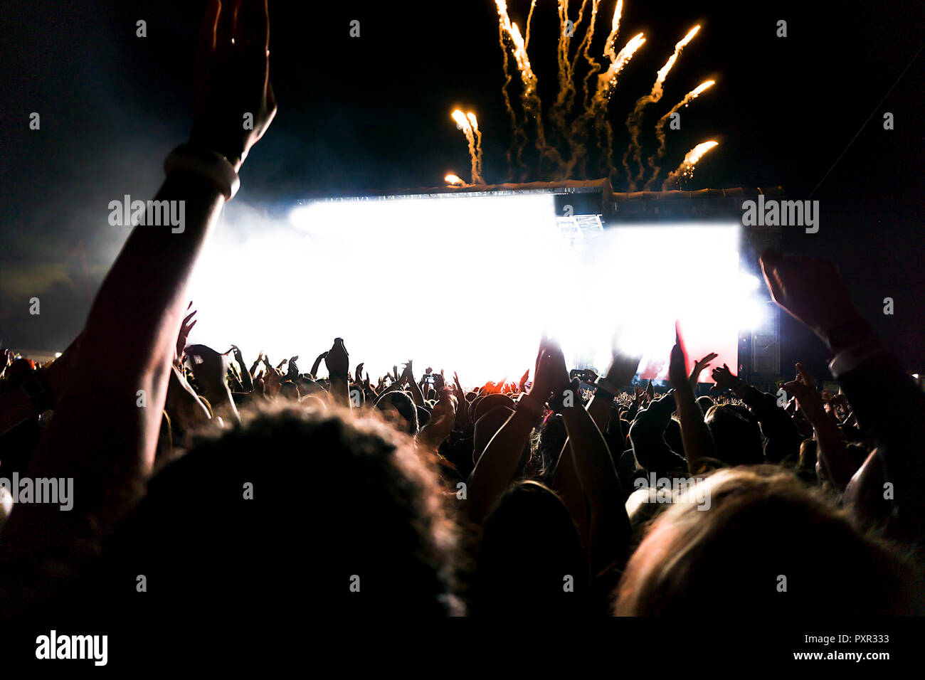 A silhouettes of concert crowd in front of bright stage lights. Dark ...