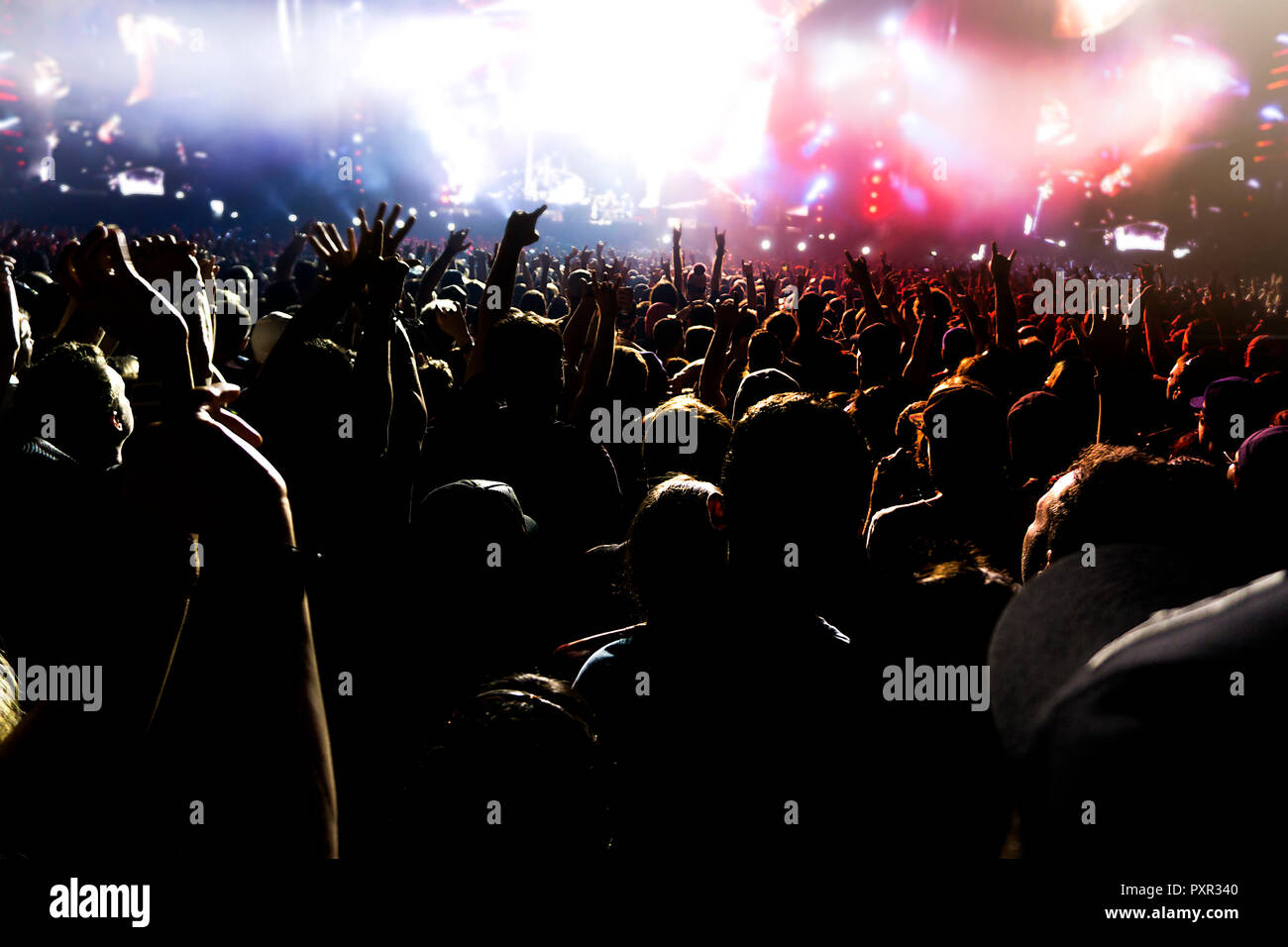 A silhouettes of concert crowd in front of bright stage lights. Dark ...