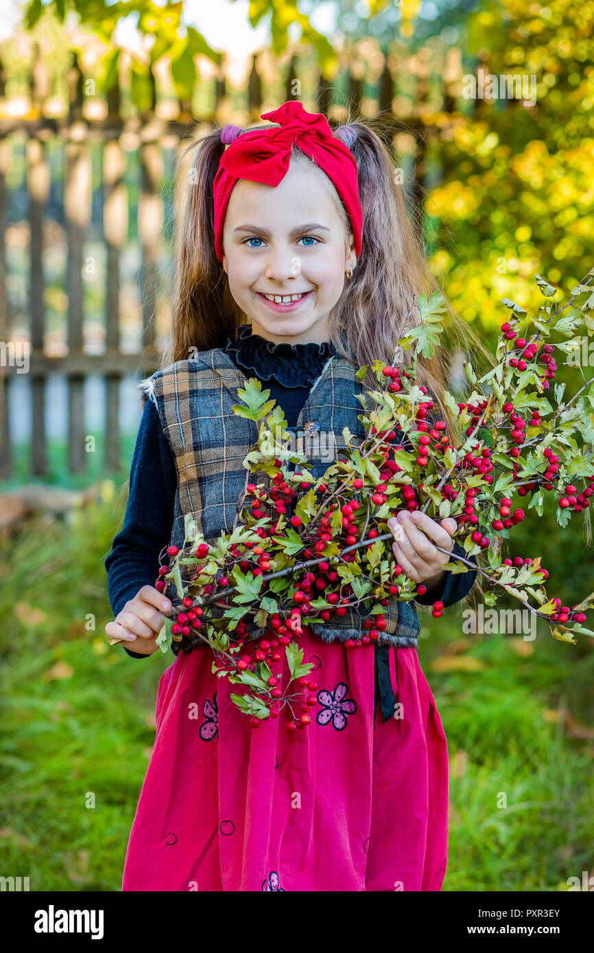 A branch of hawthorn in the hands of a cute girl in the garden. Autumn ...