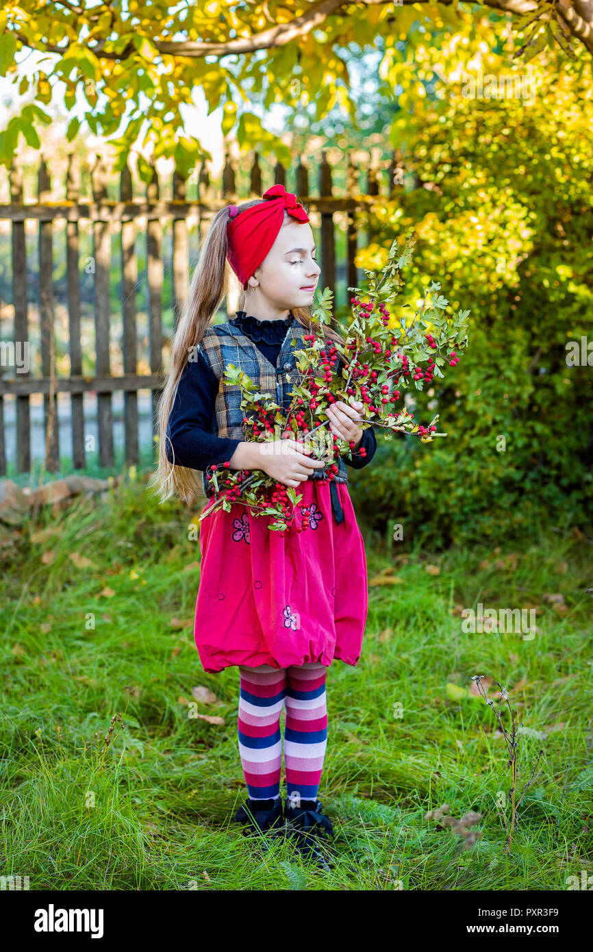 A branch of hawthorn in the hands of a cute girl in the garden. Autumn ...