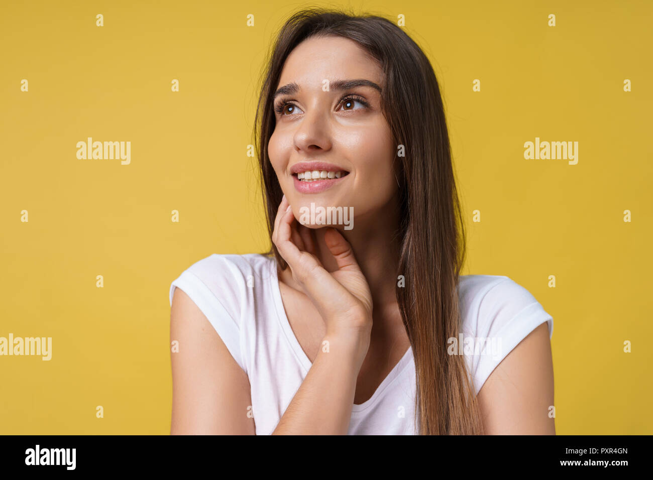 Happy cheerful young woman with joyful and charming smile isolated over yellow background Stock ...