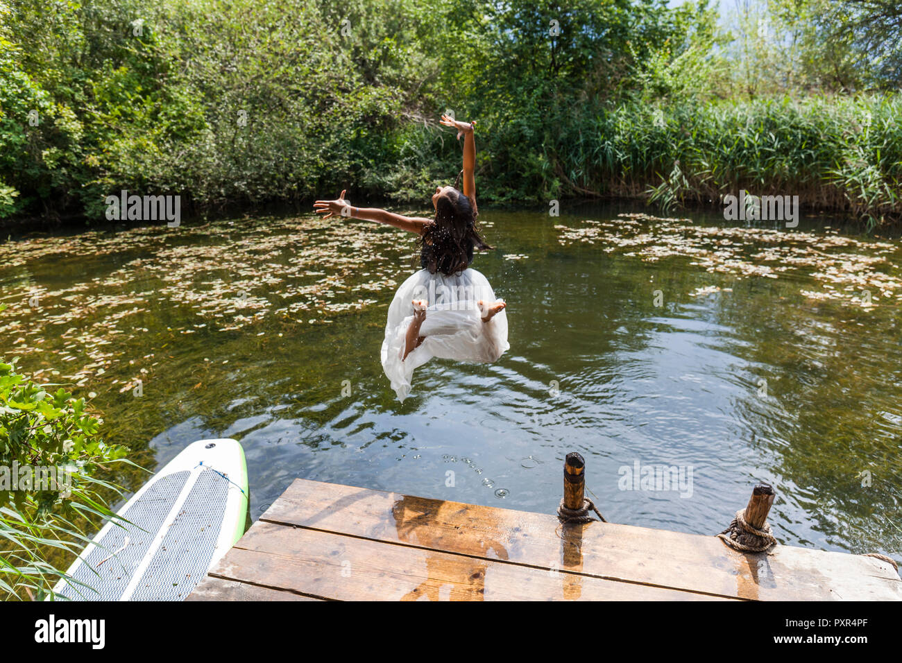 Carefree girl jumping into pond Stock Photo - Alamy