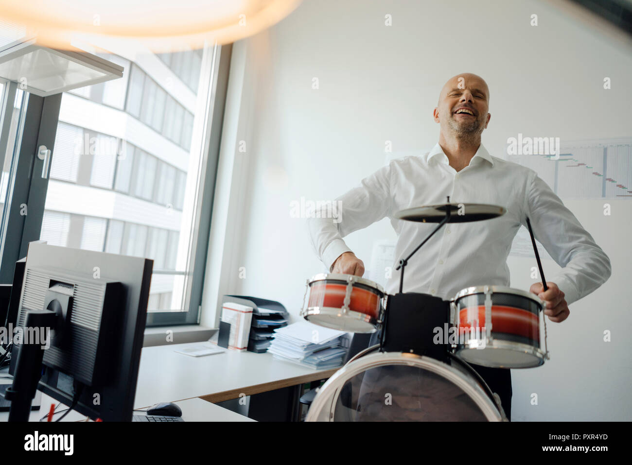 Businessman making noise with drums in his office Stock Photo - Alamy