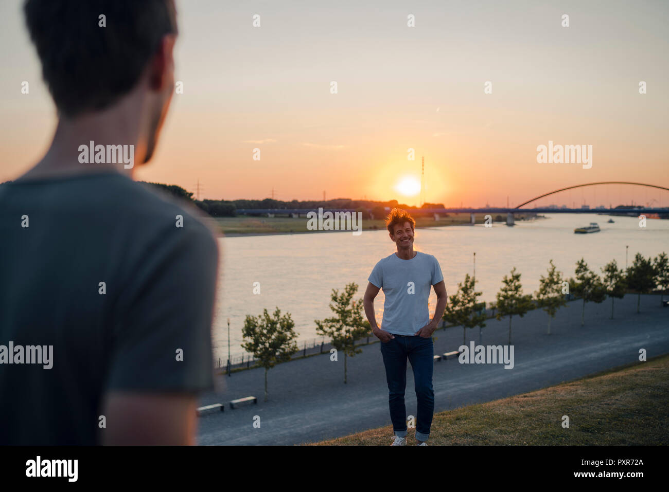 Two friends watching sunset at the river Stock Photo - Alamy