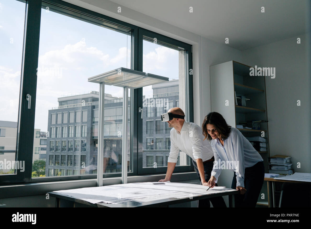 Two architects working on blueprints, man using VR glasses Stock Photo ...