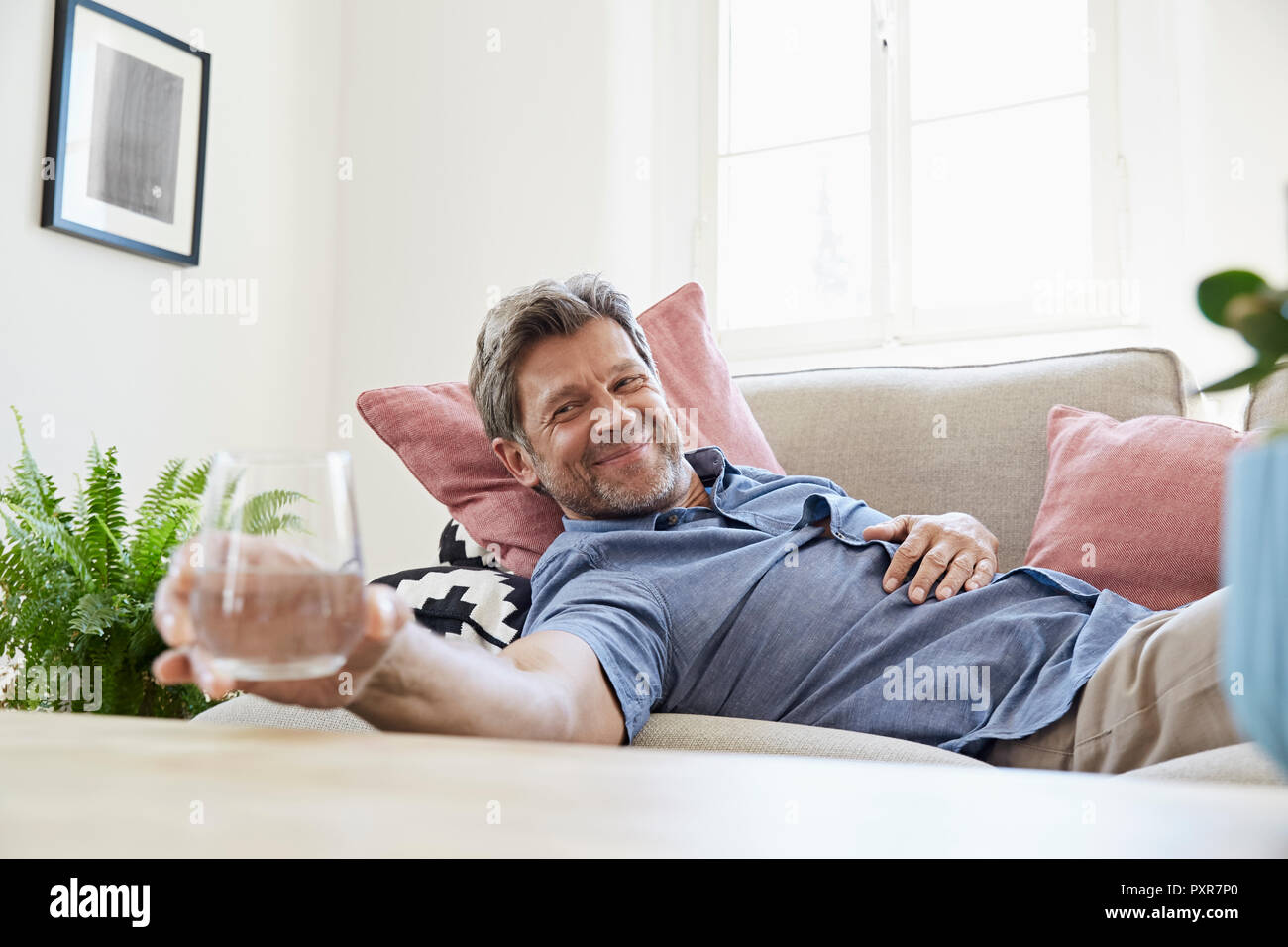 Man relaxing at home, drinking water Stock Photo - Alamy