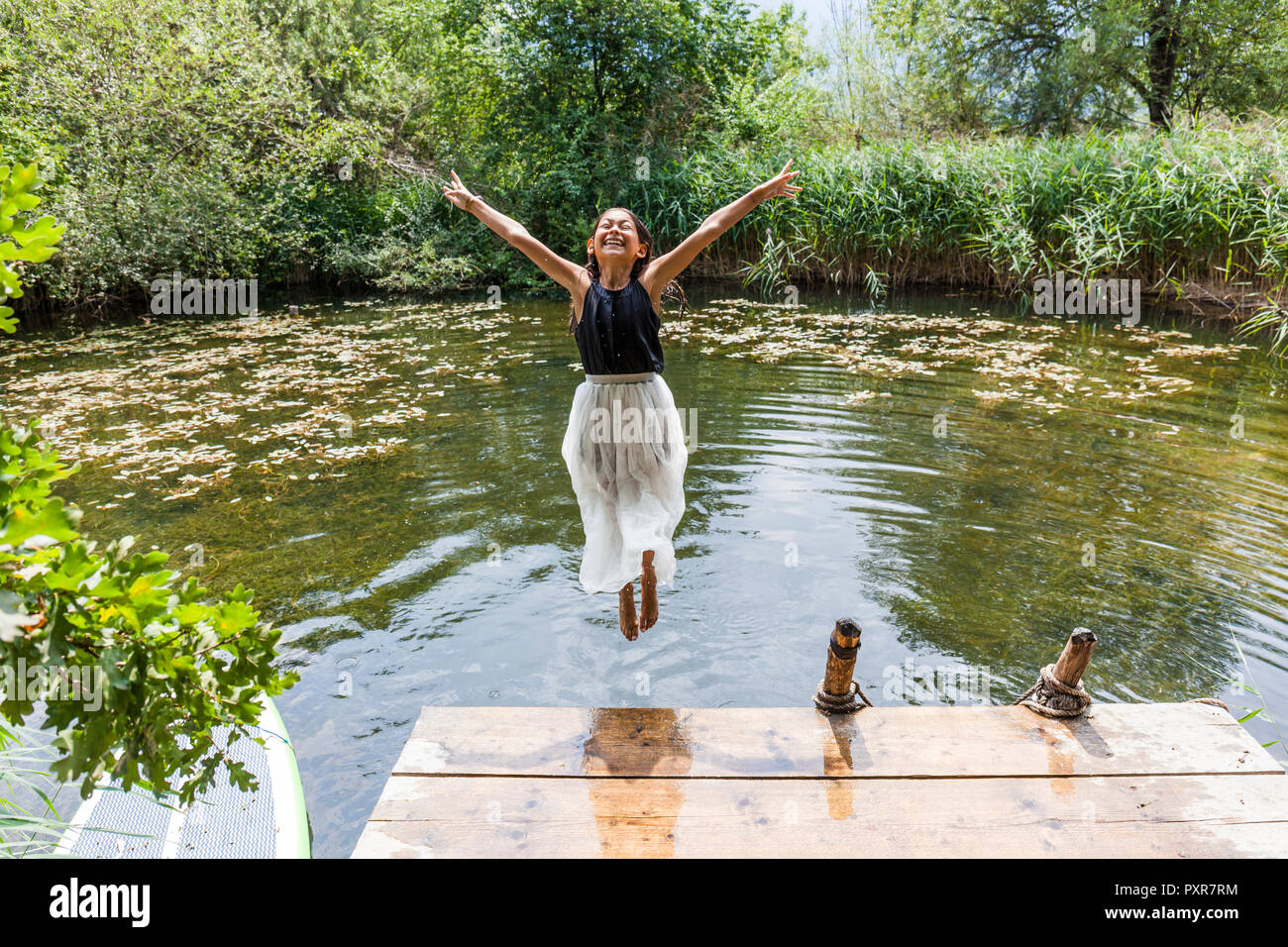 Carefree girl jumping into pond Stock Photo - Alamy
