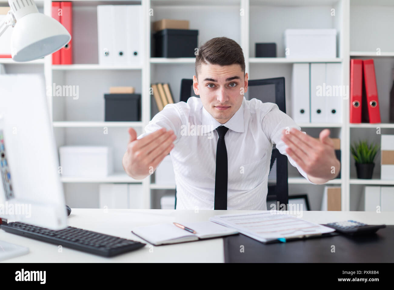 A young man sitting at a computer Desk in the office and spread his ...