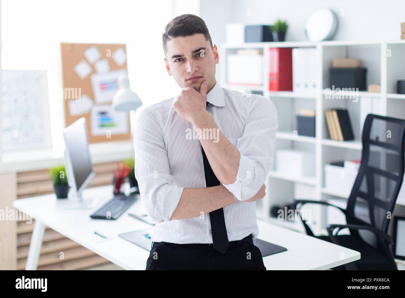 The young man stands in the office leaning on the table Stock Photo - Alamy