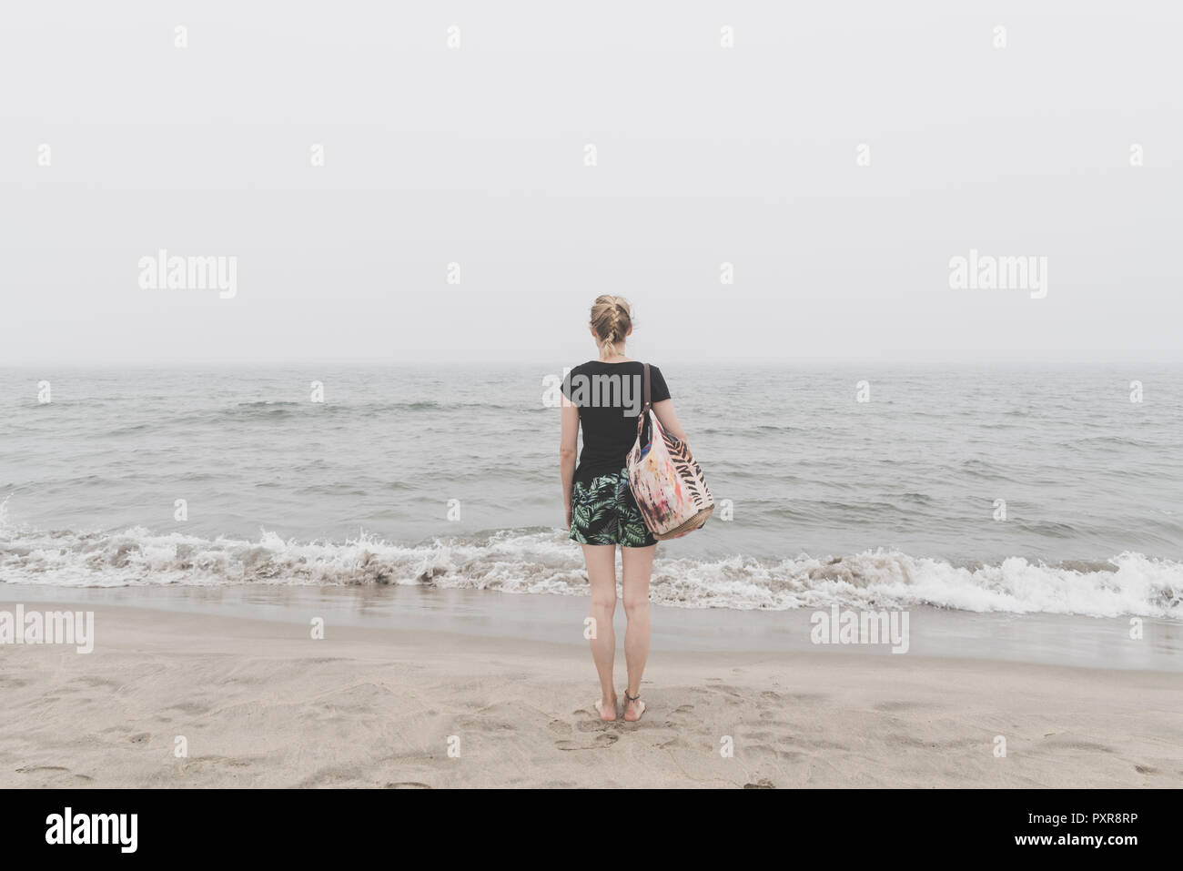 Back view of woman standing on the beach looking at distance Stock ...