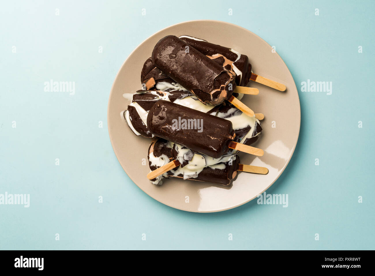 ice cream sundae in chocolate glaze in a plate on a blue background ...