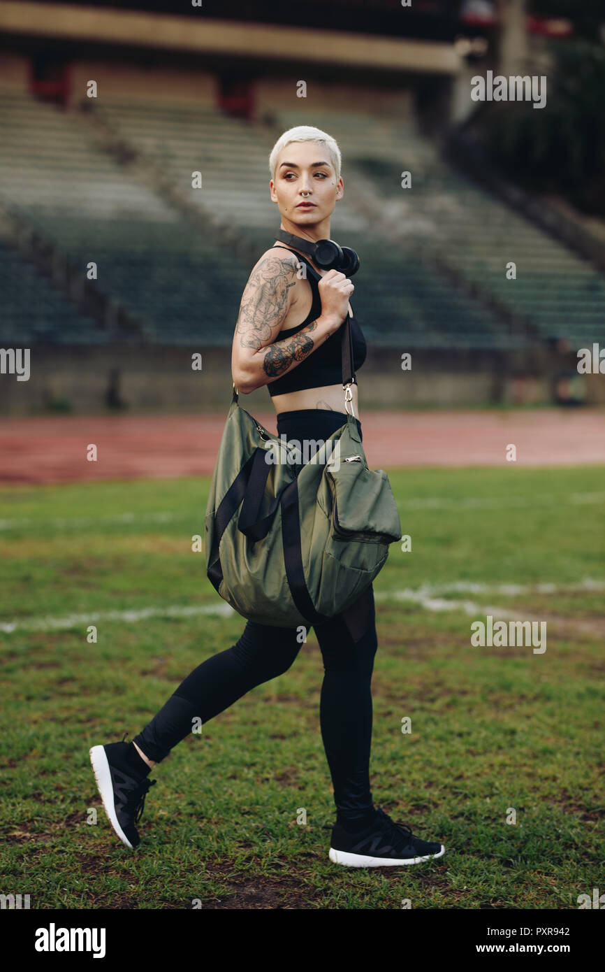 Side view of a female runner walking on grass inside an athletic ground ...