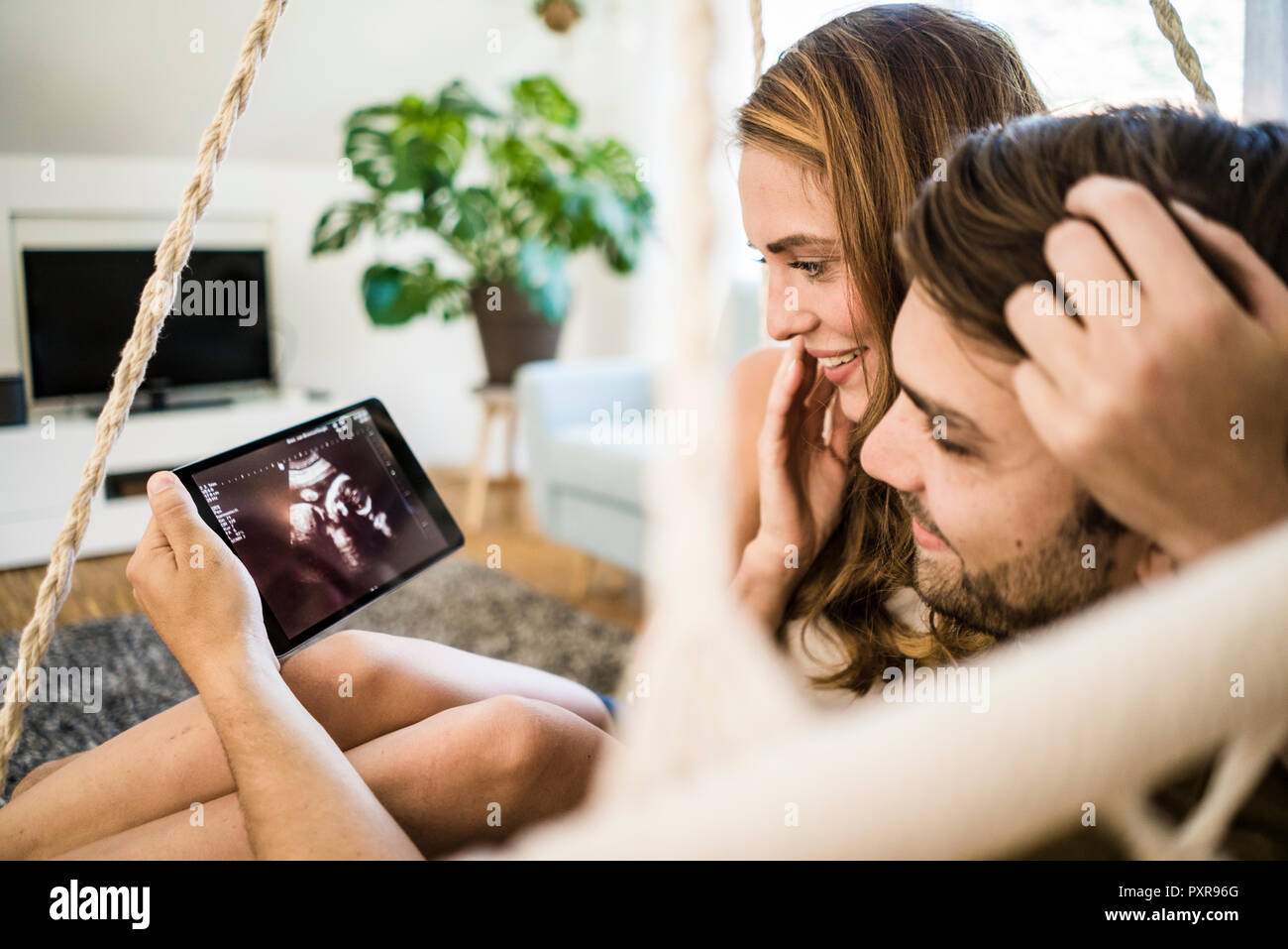 Happy affectionate couple looking at ultrasound scan on tablet Stock ...