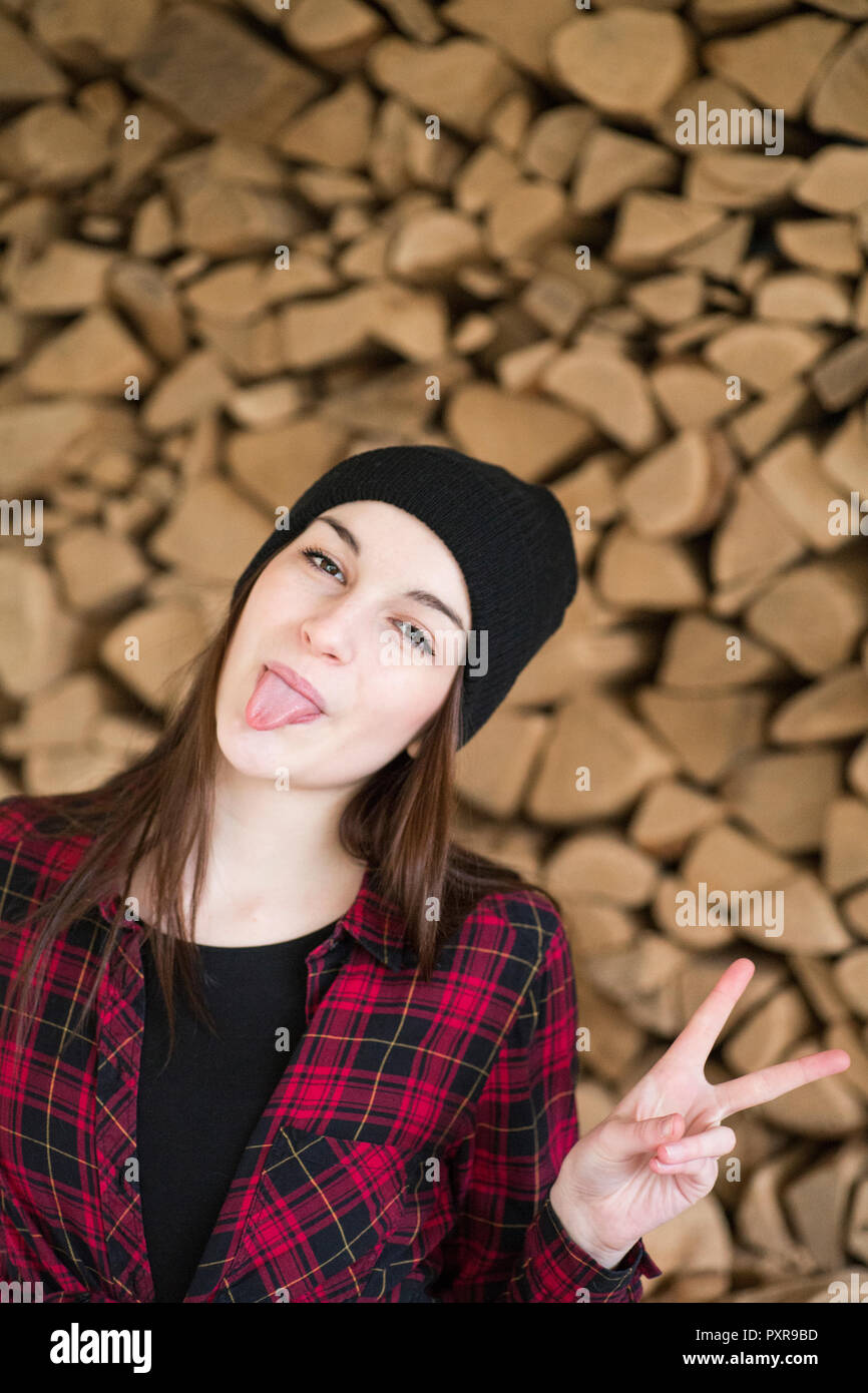Portrait young woman sticking out tongue showing victory sign hi-res ...