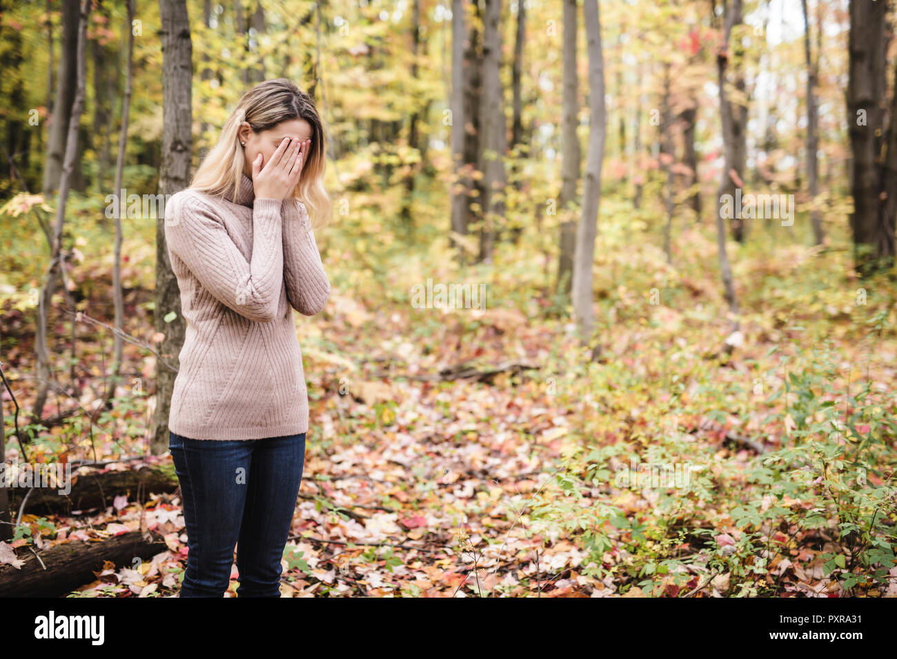 A Sad woman in park during autumn weather hiding face in hand, feeling ...
