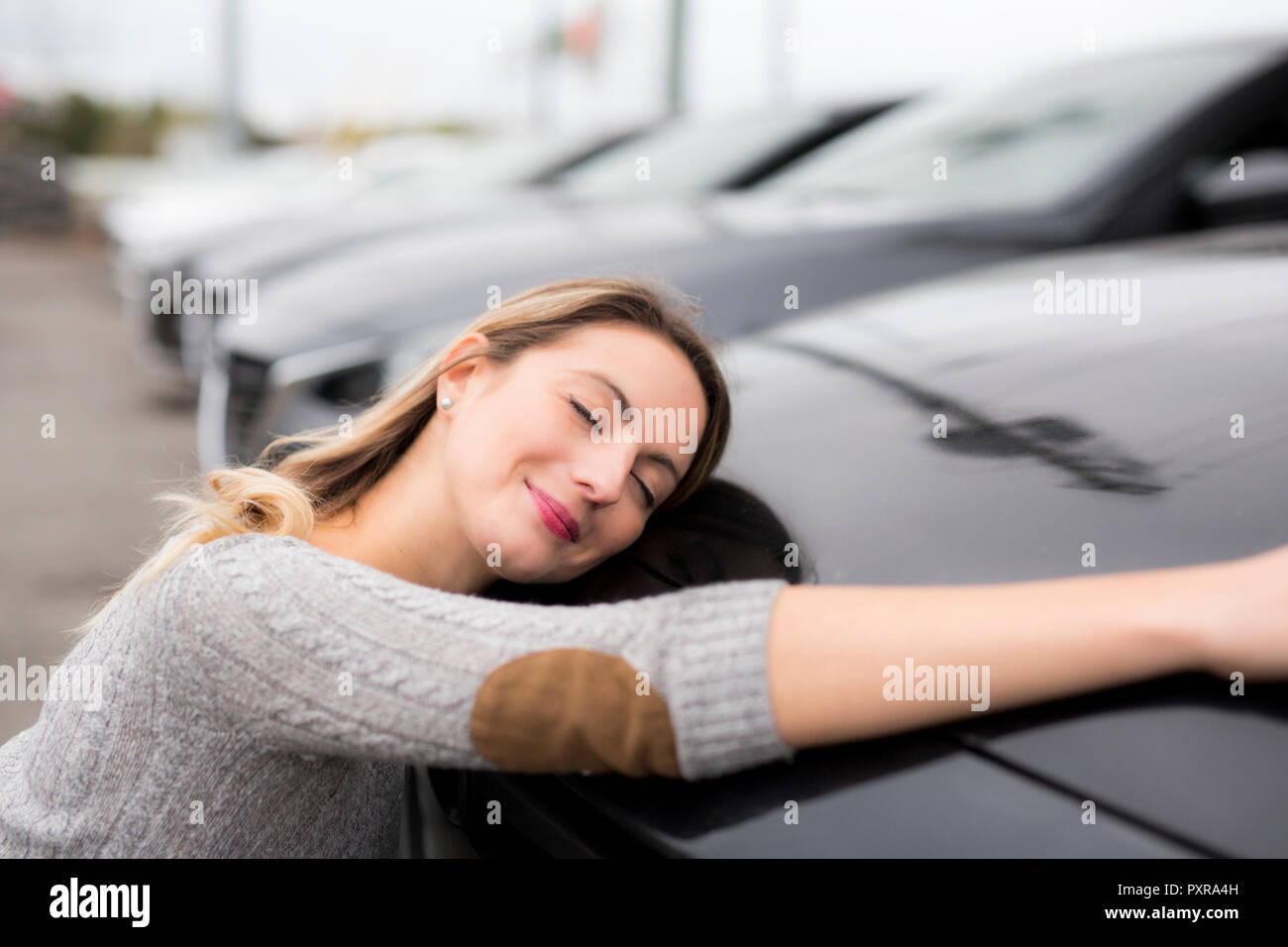 Jolly young female driver hugging her new car Stock Photo - Alamy