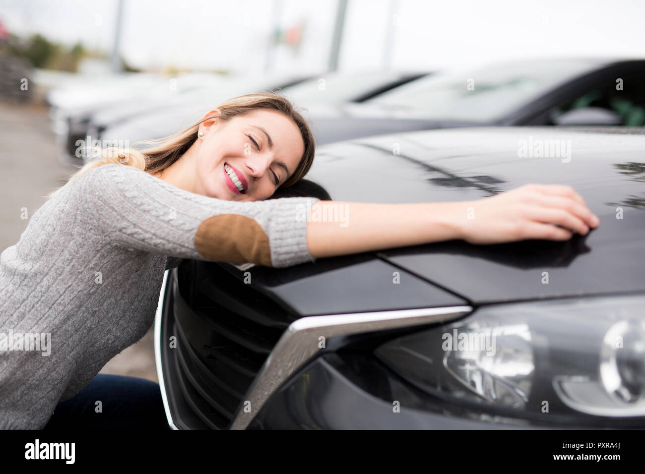 Jolly young female driver hugging her new car Stock Photo - Alamy