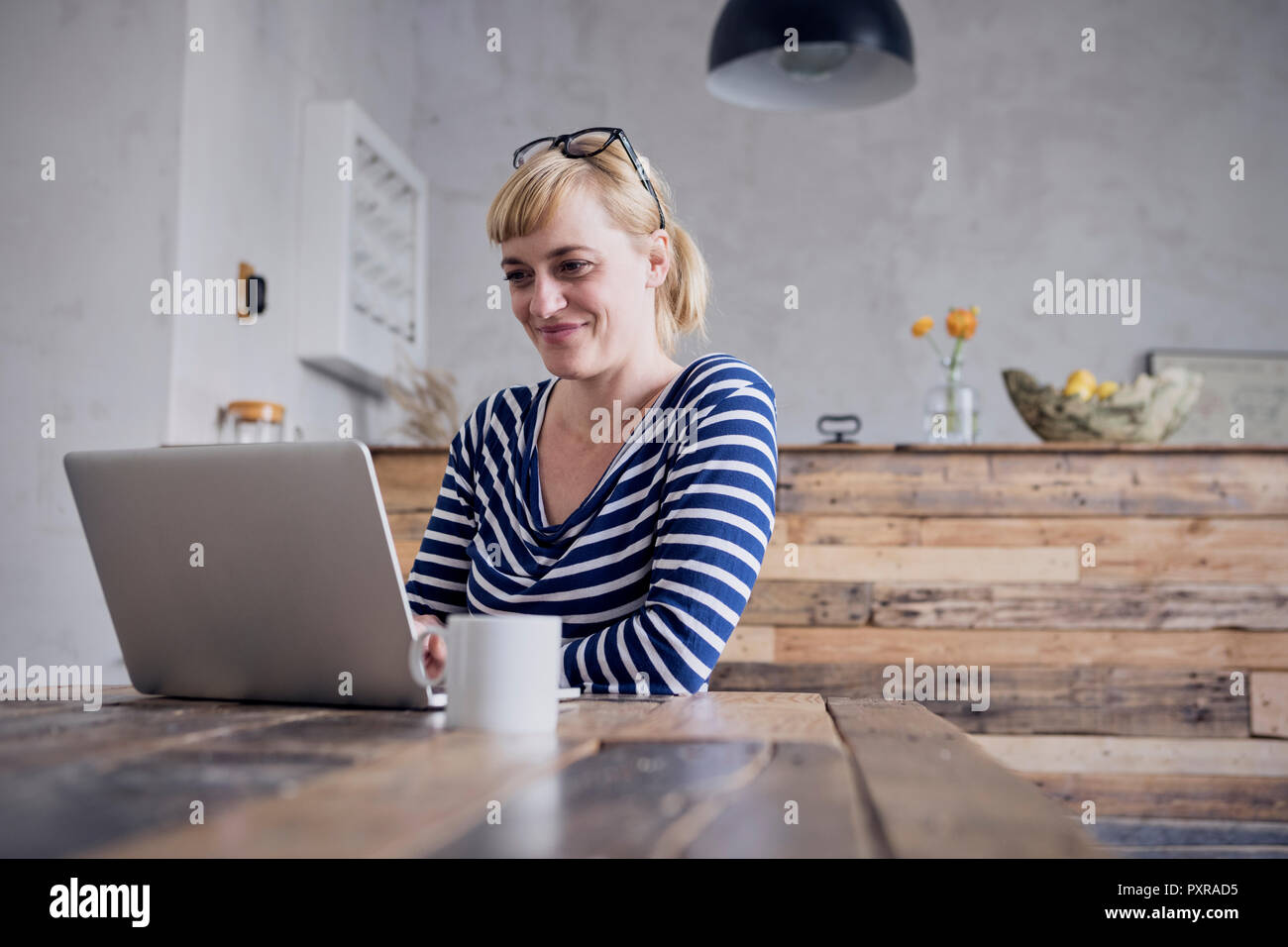 Business woman using laptop sitting on window ledge Stock Photo - Alamy