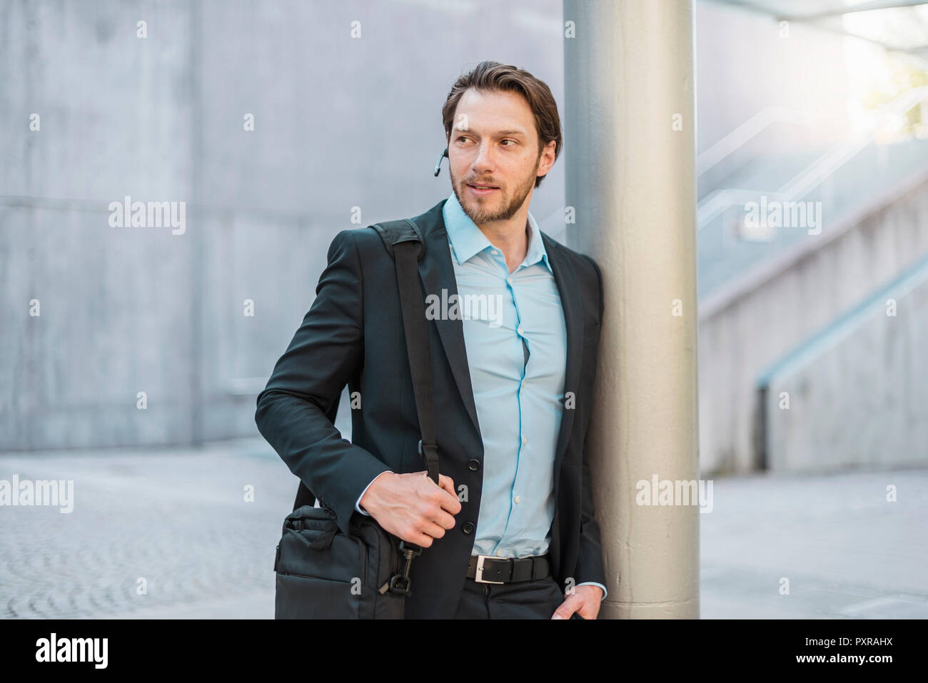 Businessman with laptop bag wearing headset outdoors Stock Photo - Alamy