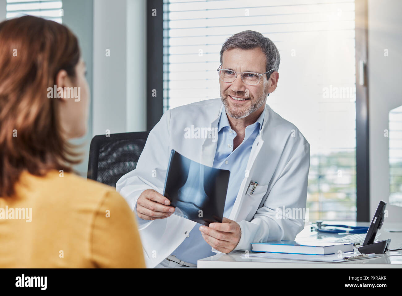 Physician patient talk, doctor holding x-ray image Stock Photo - Alamy