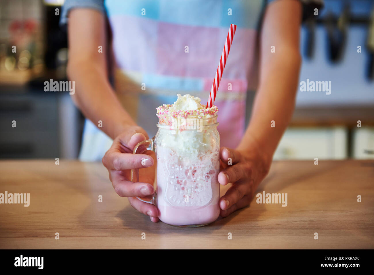 Waitress serving glass of strawberry milkshake Stock Photo - Alamy