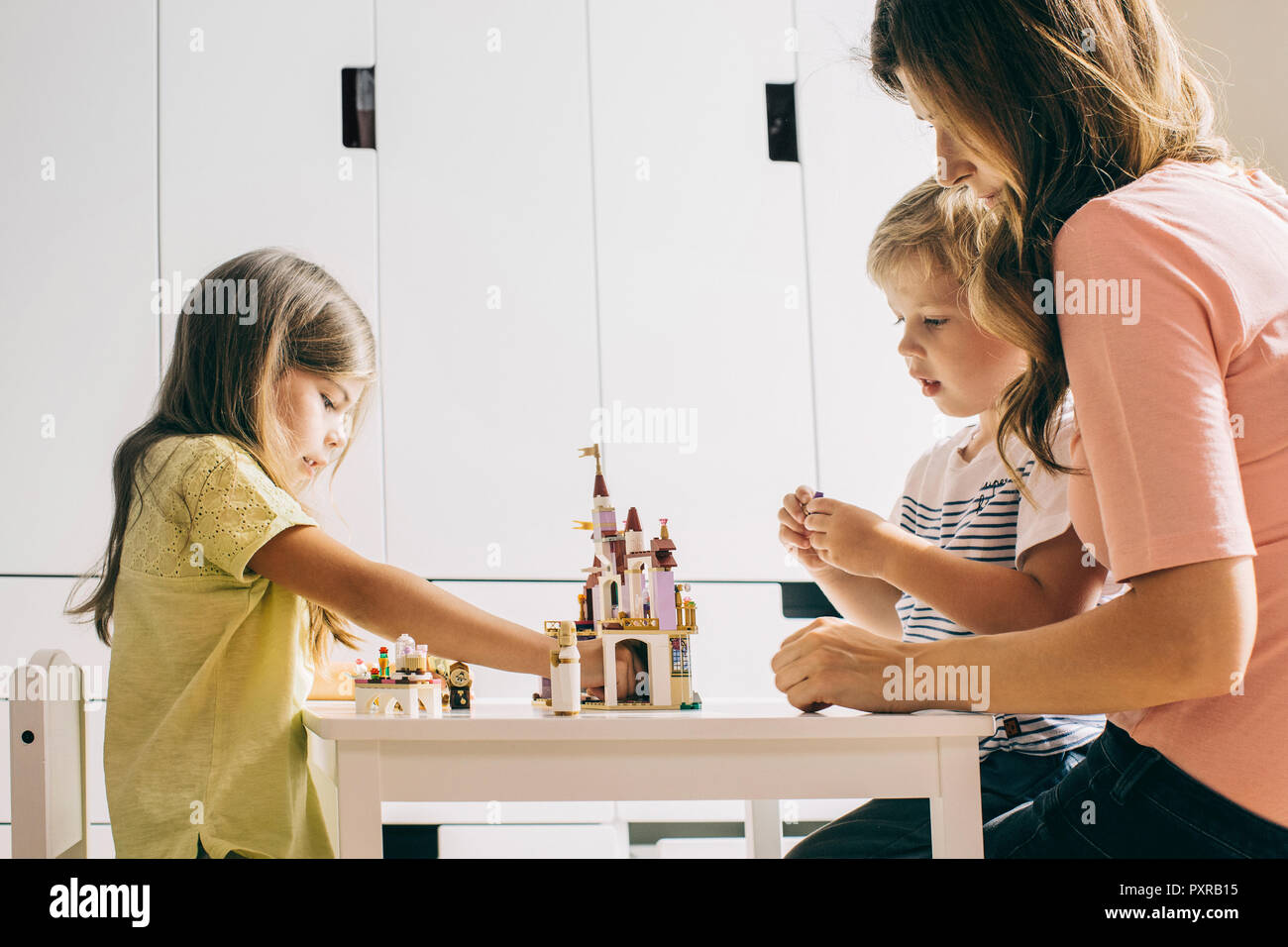 Mother with two children building up toy castle at home Stock Photo - Alamy
