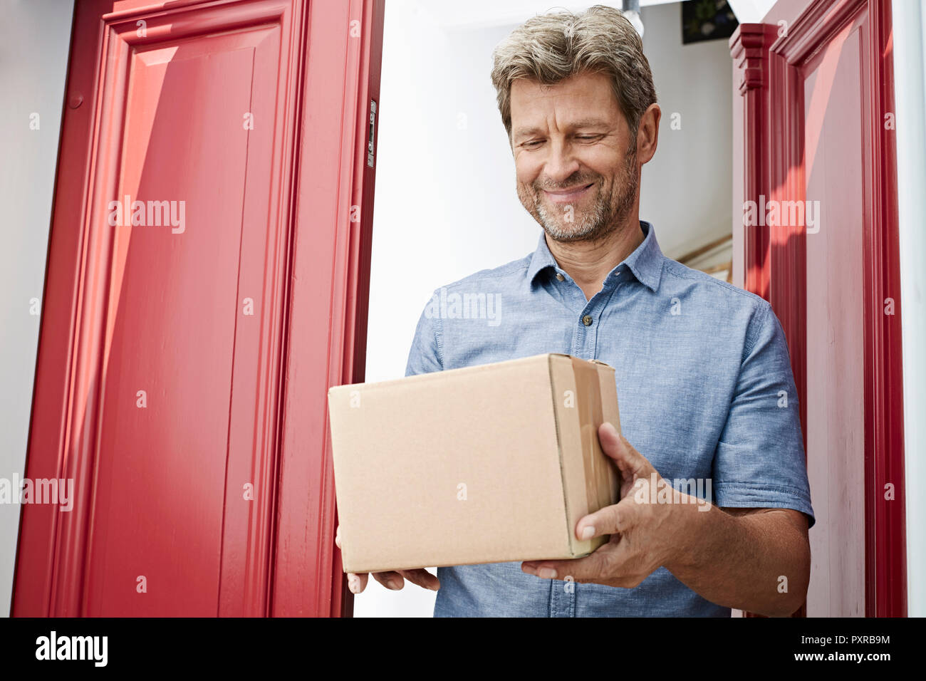 Mature man receiving a package at his door Stock Photo - Alamy