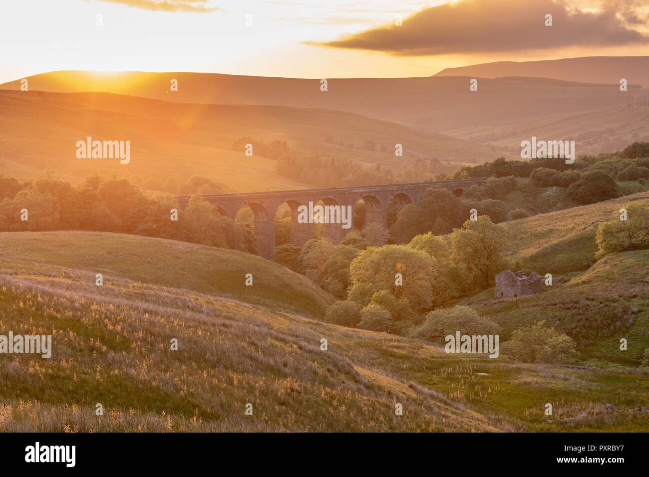 The golden summer sun sets behind the hills that surround the valley ...