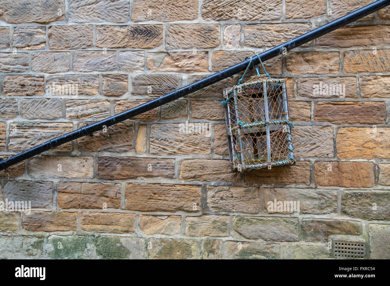 An old fishing cage hangs on a pole, Robin Hood's bay, Yorkshire, UK ...