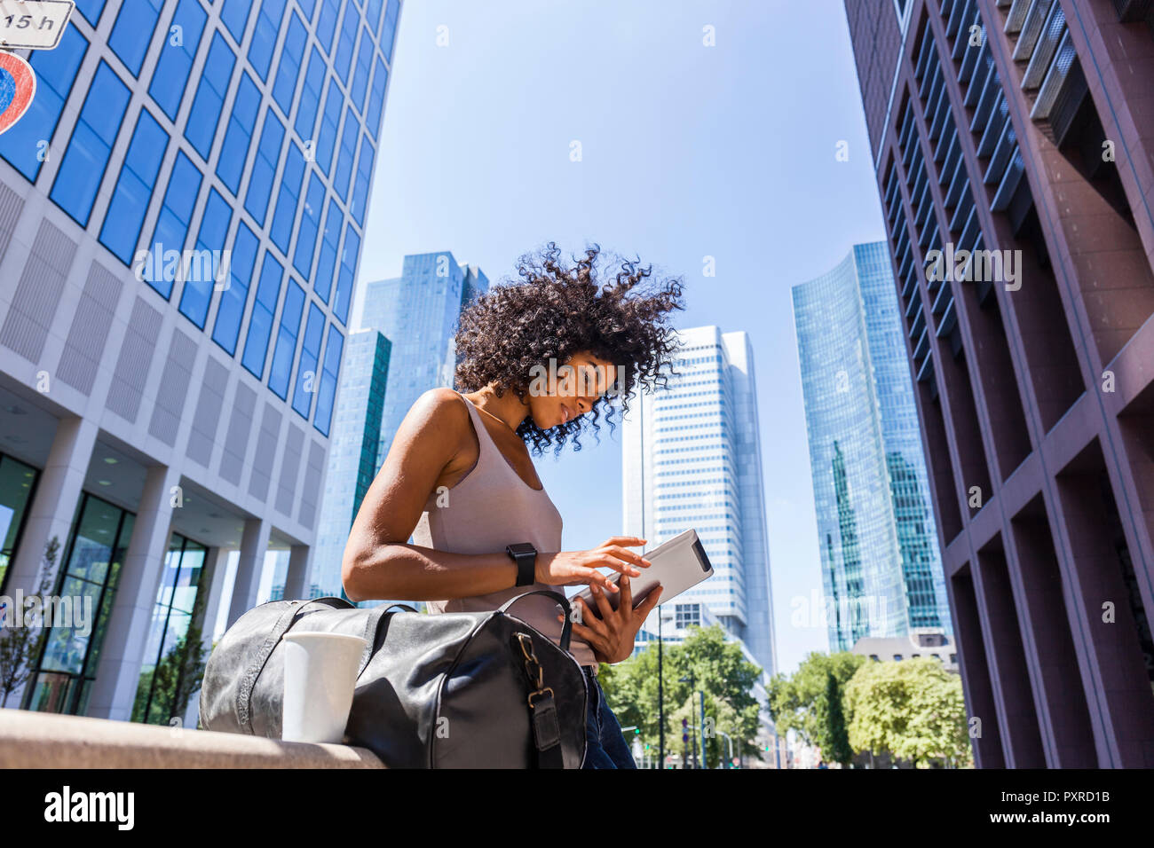 Germany, Frankfurt, young woman with travelling bag and coffee to go ...