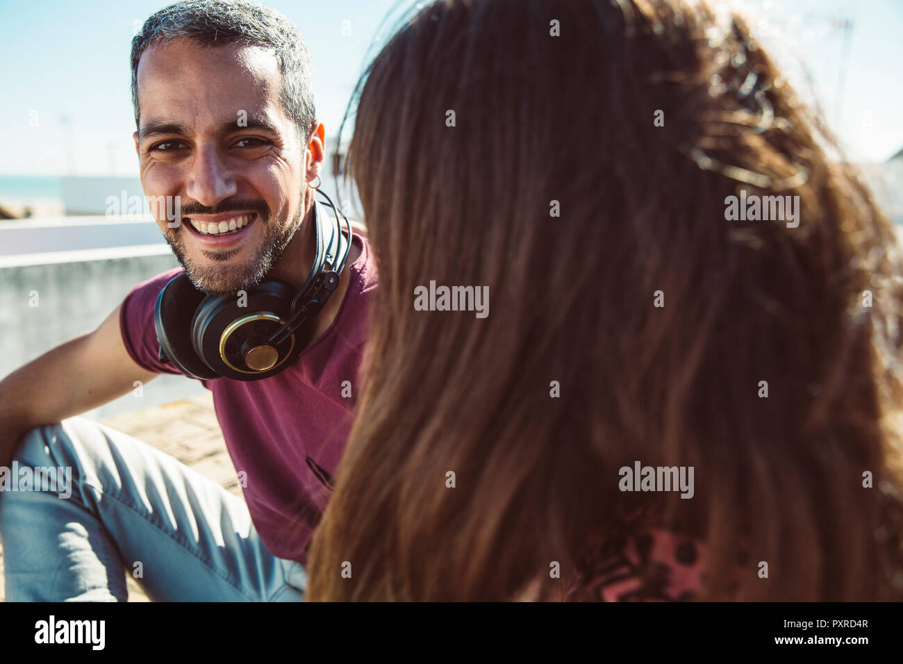 Happy couple sitting on roof, talking, enjoying summer Stock Photo - Alamy