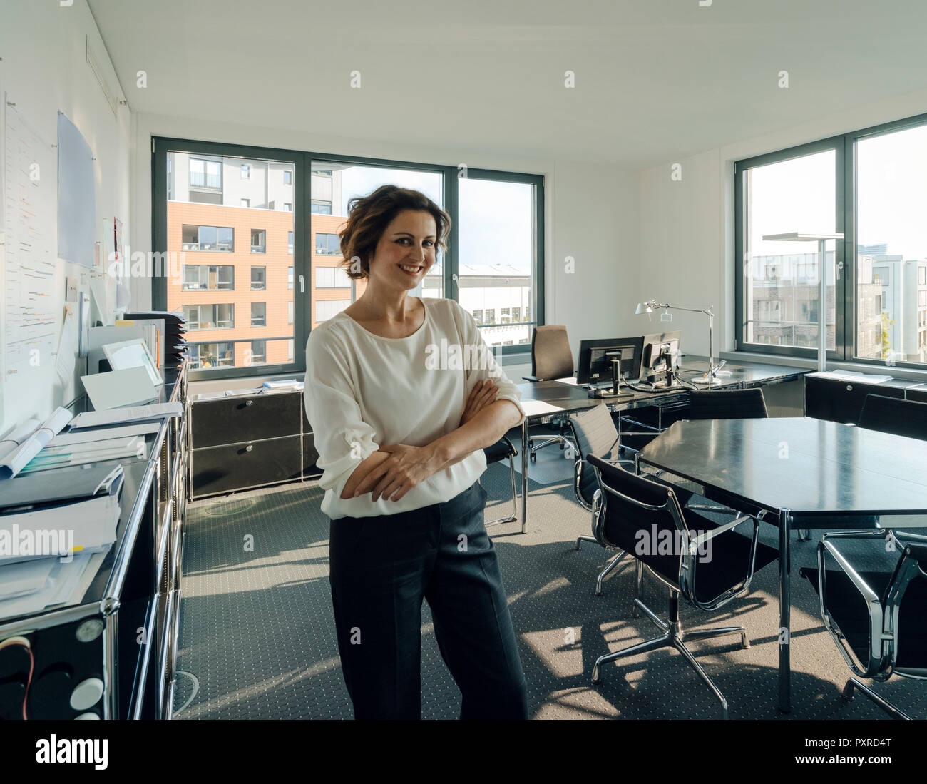 Successful businesswoman standing in her office with arms crossed Stock ...