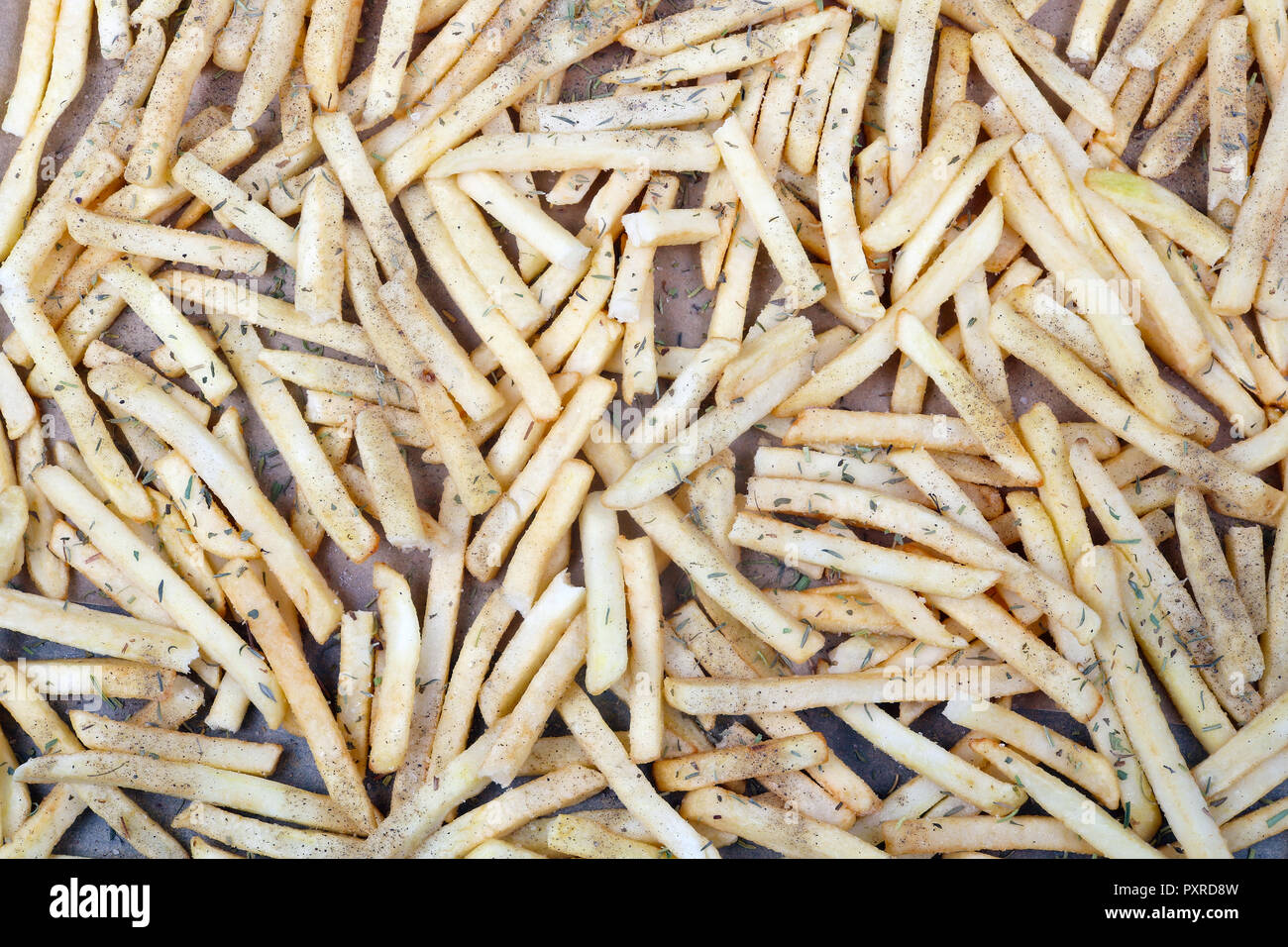 The strips of potatoes on a baking sheet sprinkled with salt pepper and ...