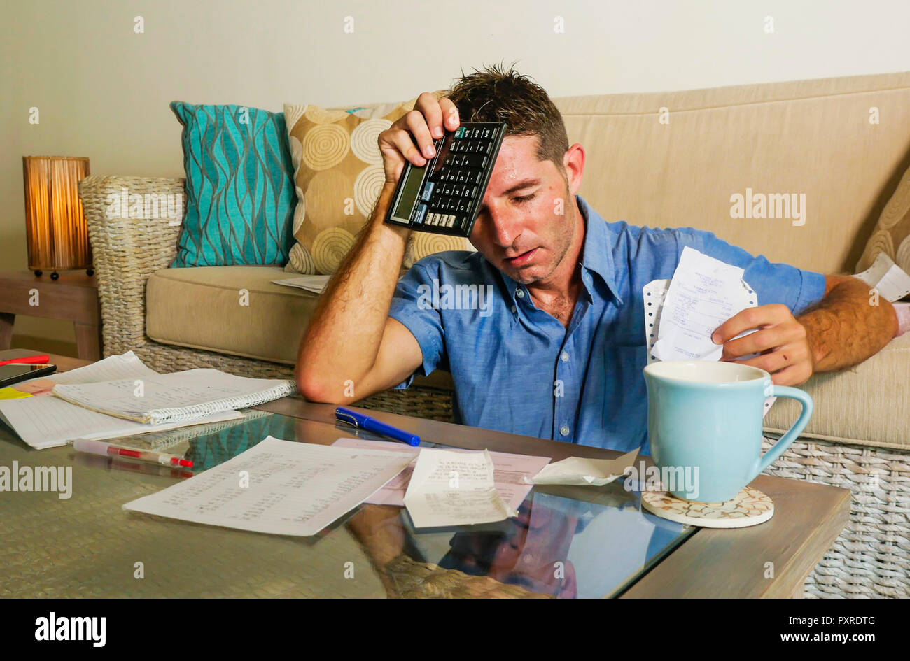 young attractive worried and stressed man at home calculating month tax ...