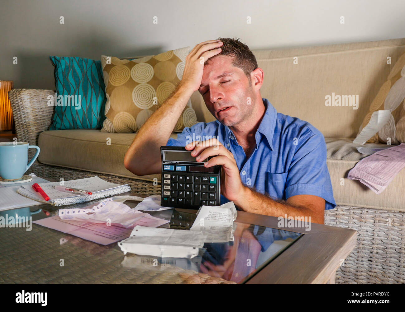 young attractive worried and stressed man at home calculating month tax ...