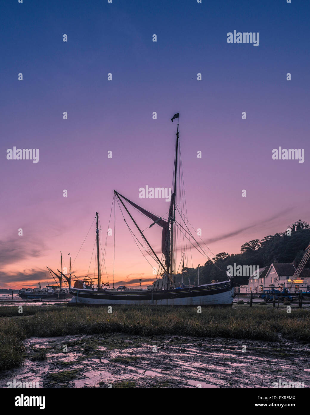 Three Thames sailing barges lie on the mud at Pin MIll as the day ...