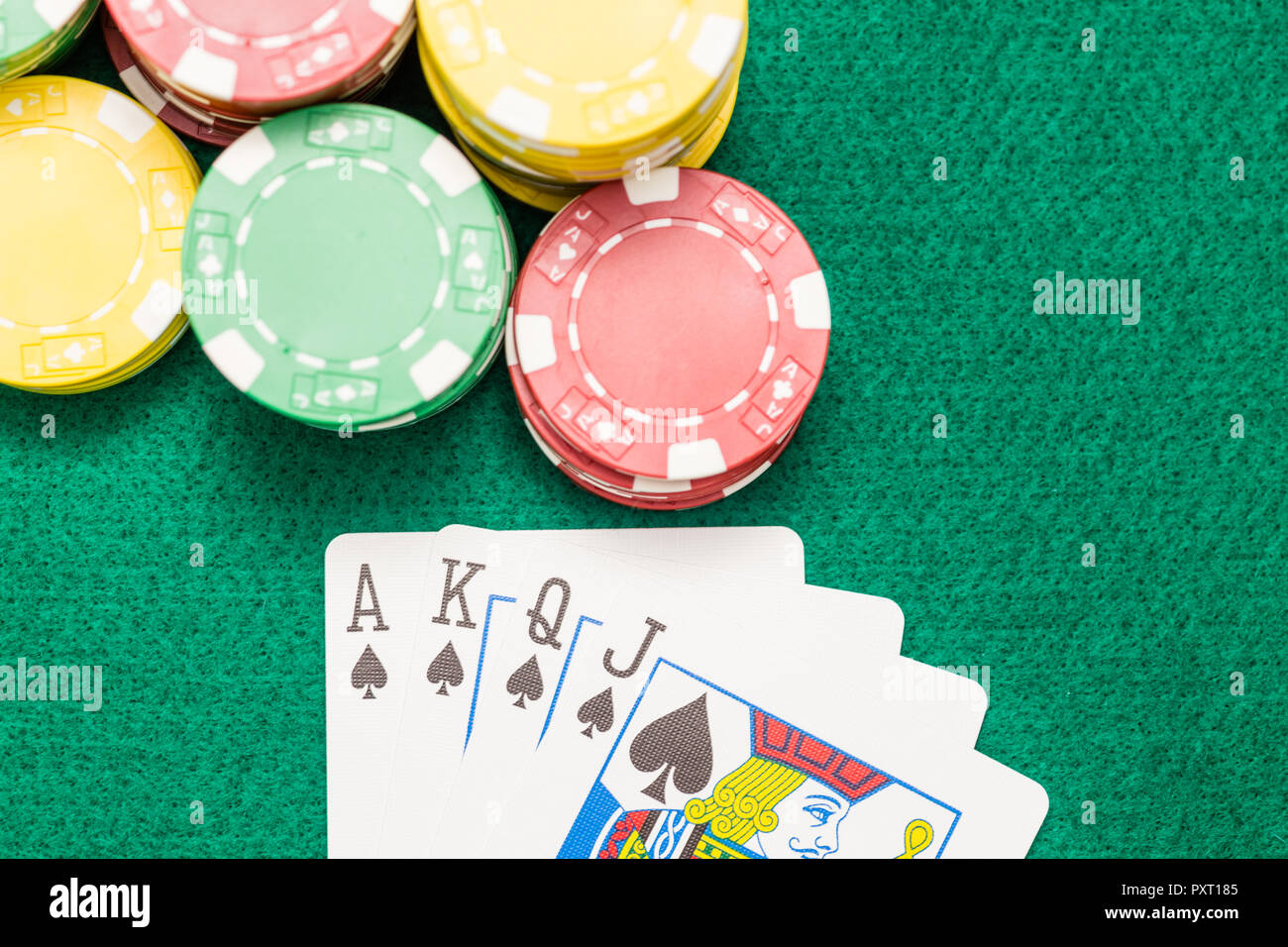 Casino chips and ace, king queen jack of spades on green table Stock ...
