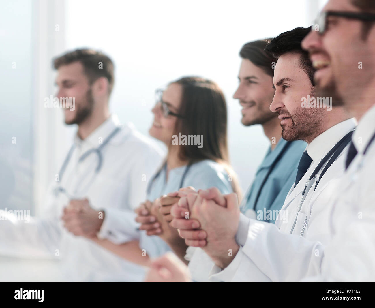 doctors sit in a row and hold hands of each other Stock Photo - Alamy