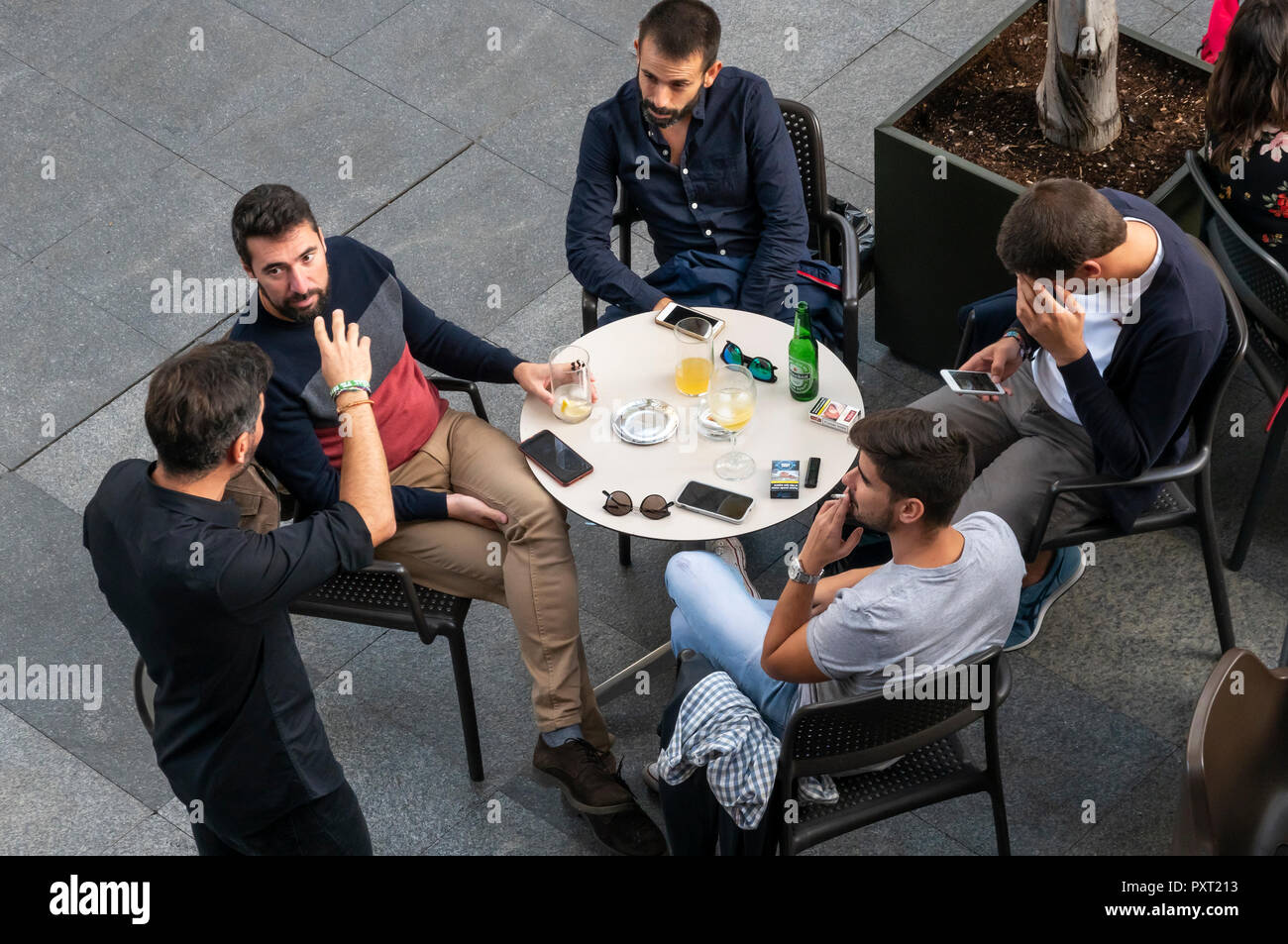 Five young Spanish men sharing a talk and a drink at a Seville cafe ...