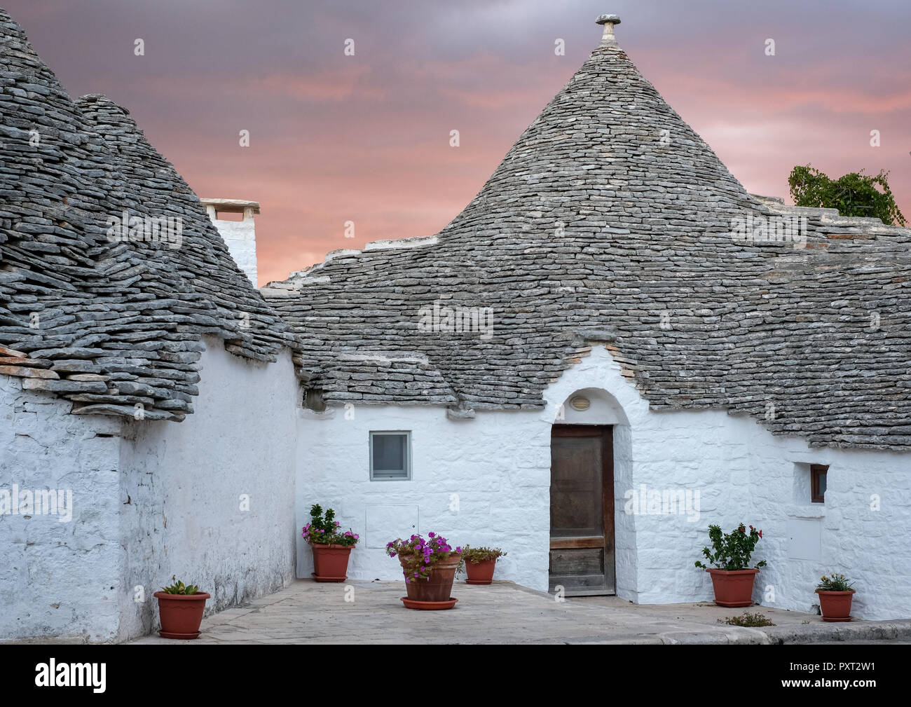 Dry stone, white washed, conical roofed trulli houses on a street in ...
