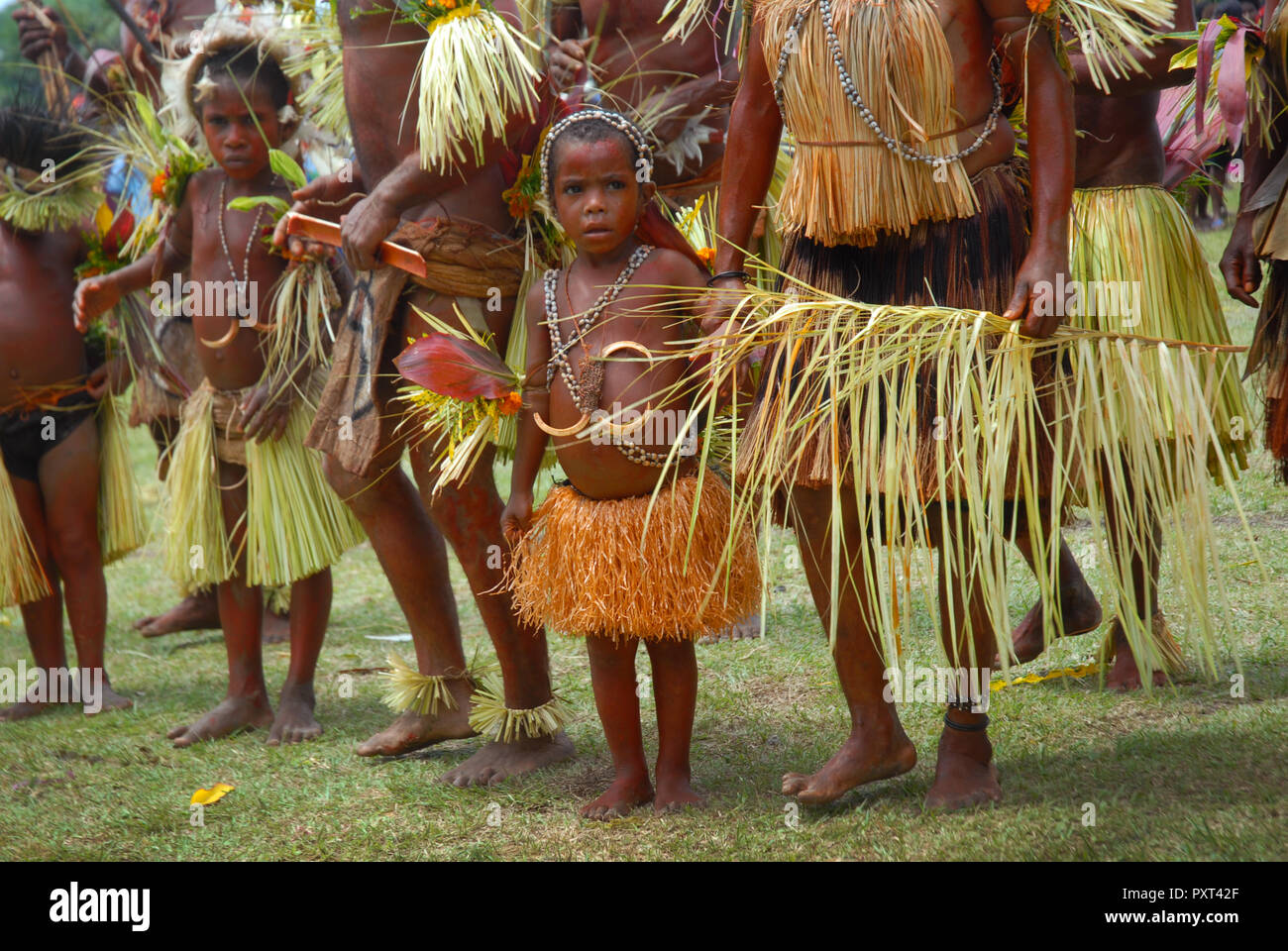 Colourfully dressed and face painted children dancing as part of a Sing ...