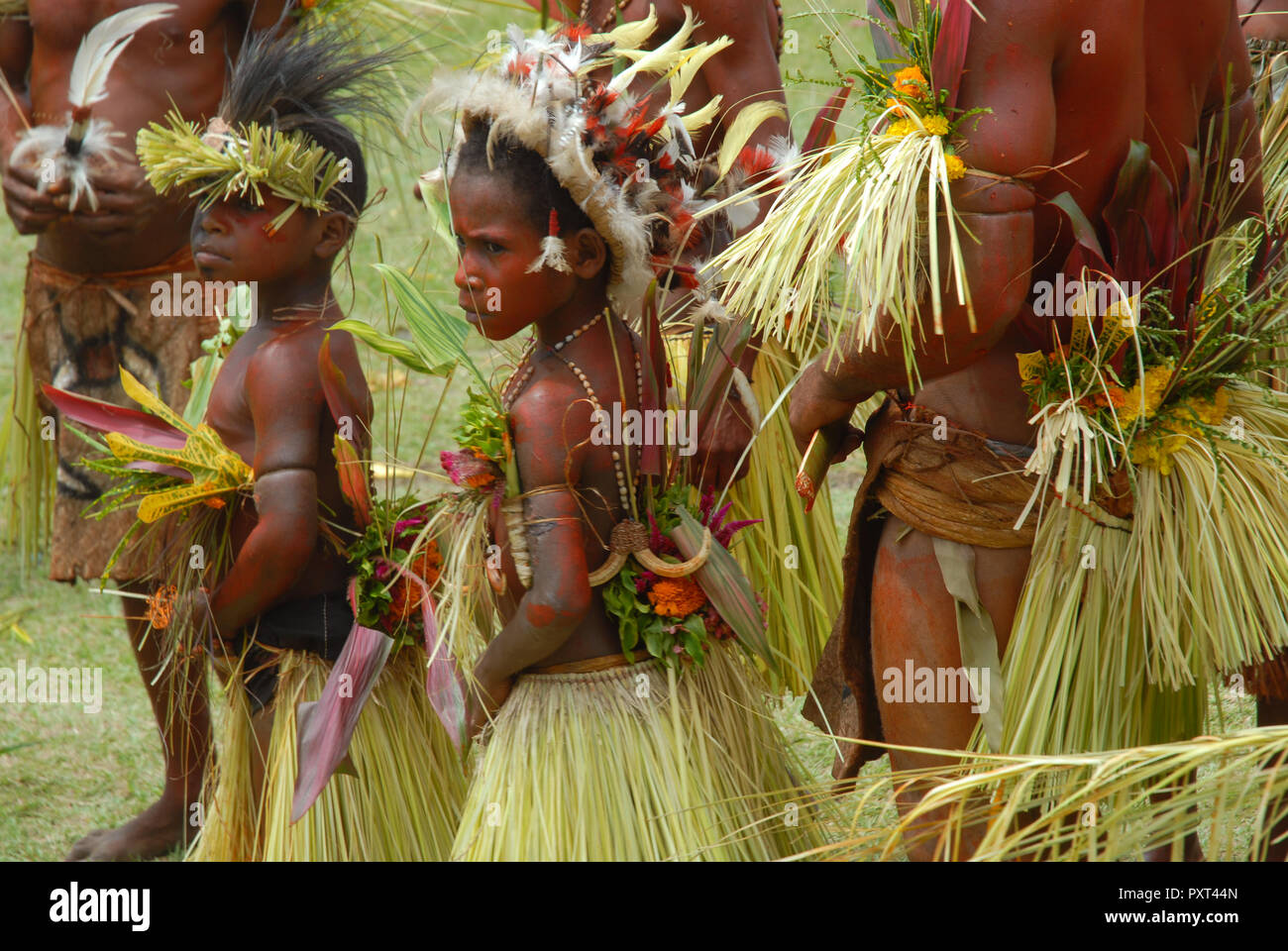Colourfully dressed and face painted children dancing as part of a Sing ...