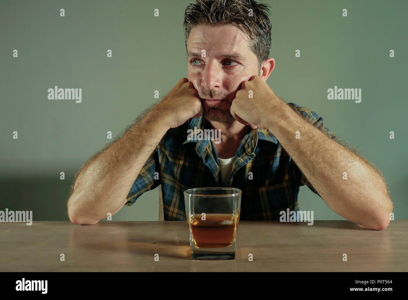 isolated portrait of young drunk addict and alcoholic man drinking whiskey glass intoxicated ...