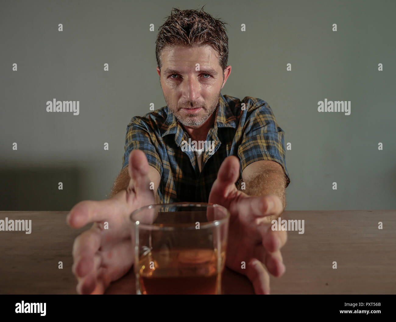isolated portrait of young drunk addict and alcoholic man drinking whiskey glass intoxicated ...