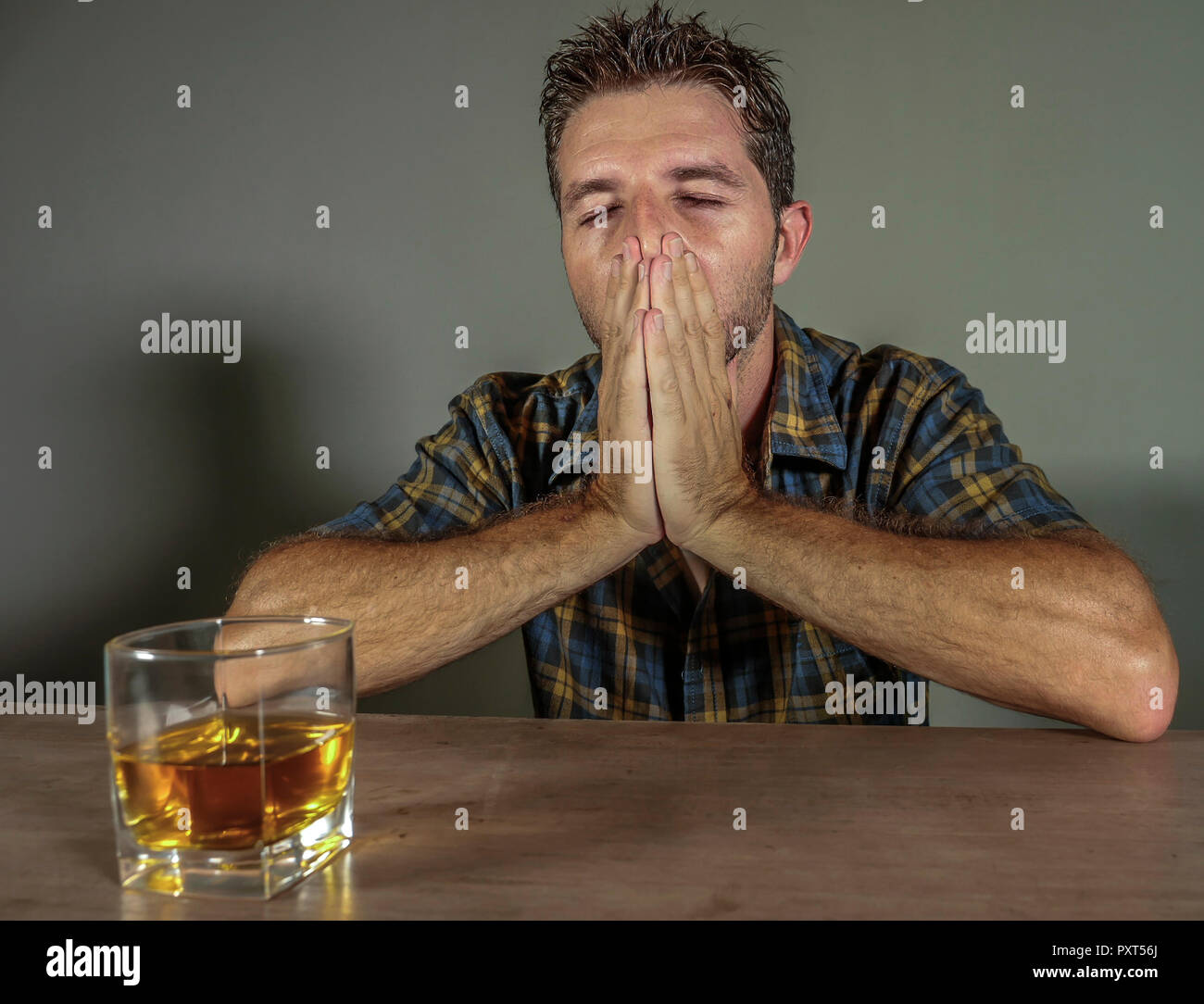isolated portrait of young drunk addict and alcoholic man drinking whiskey glass intoxicated ...