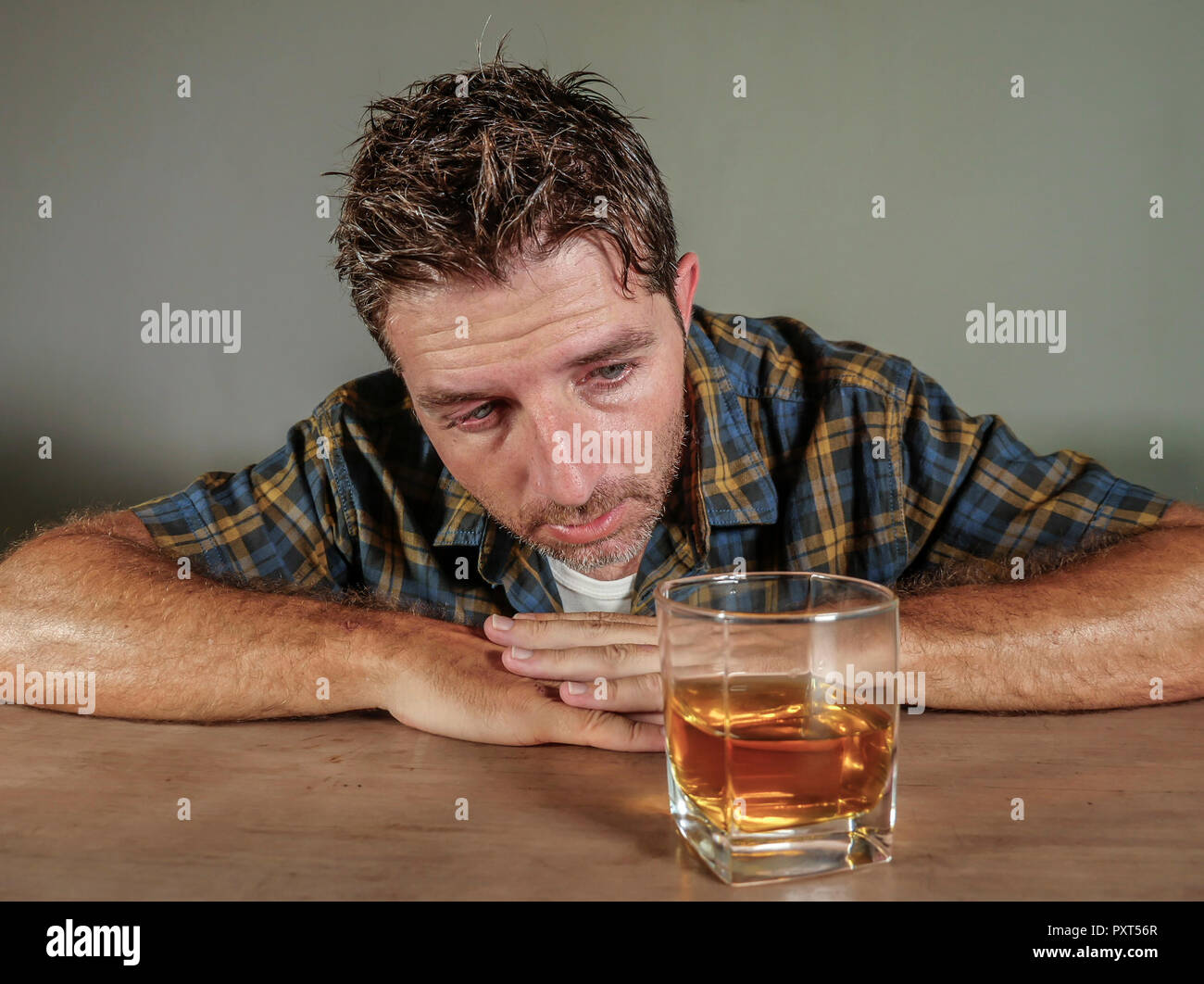 isolated portrait of young drunk addict and alcoholic man drinking whiskey glass intoxicated ...