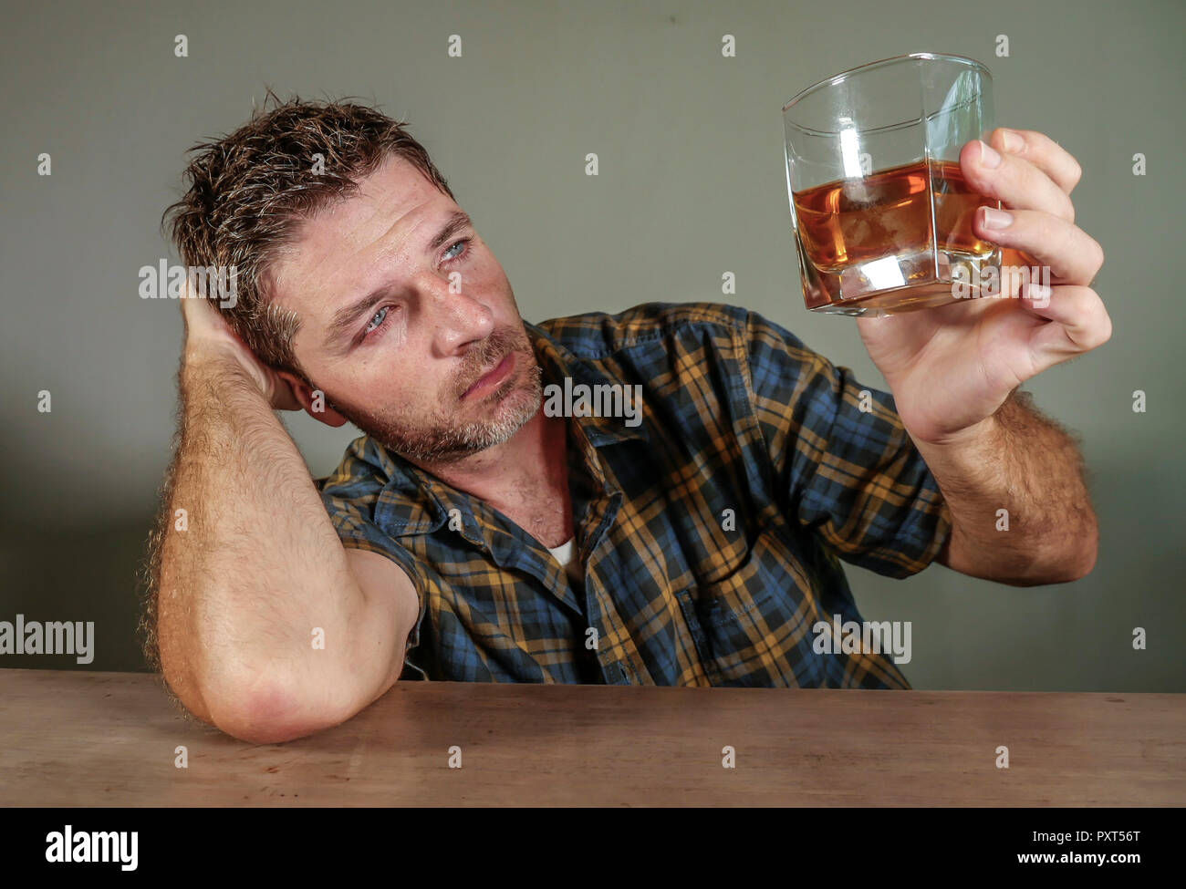 isolated portrait of young drunk addict and alcoholic man drinking whiskey glass intoxicated ...