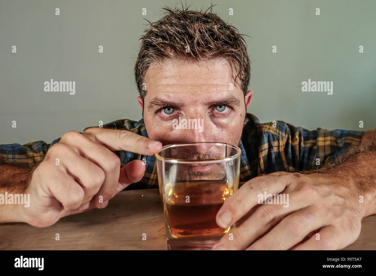 isolated portrait of young drunk addict and alcoholic man drinking whiskey glass intoxicated ...