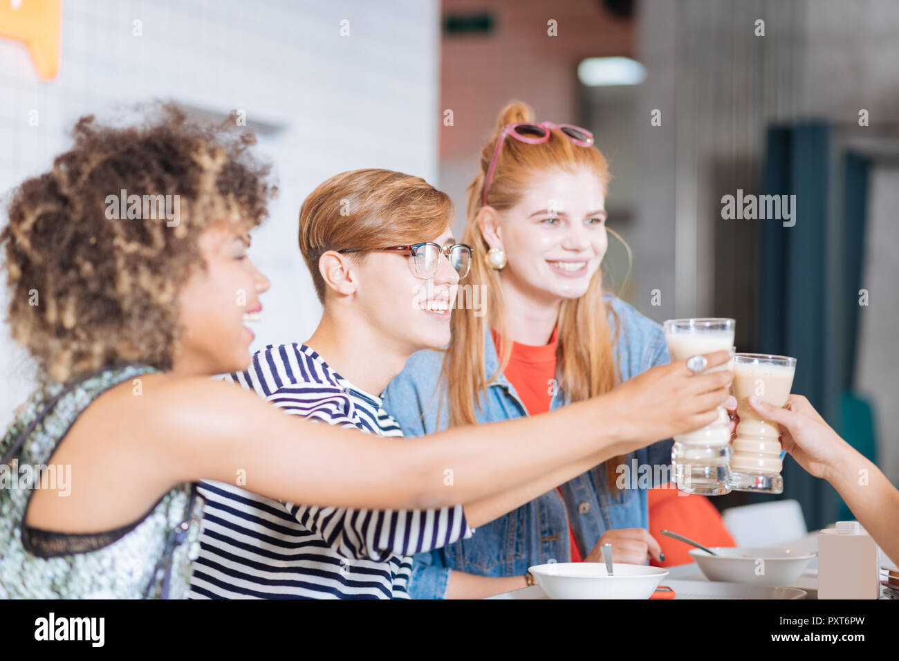 Pleased group mates touching glasses with cacao Stock Photo - Alamy
