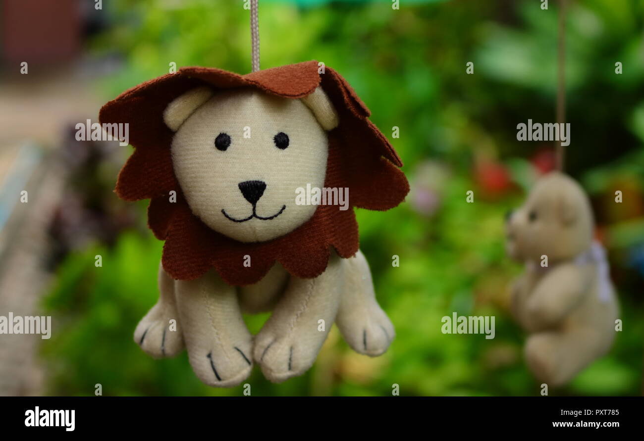 closeup face of a happy lion doll hanging from a cord in garden ...